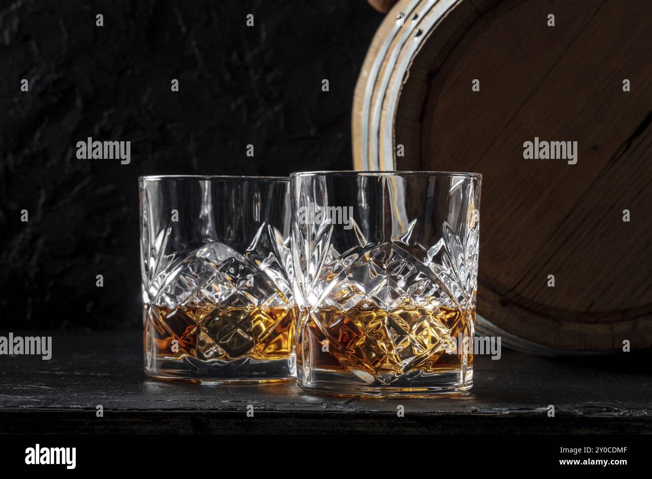 Whiskey in glasses with a barrel. Bourbon whisky and a cask on a dark ...