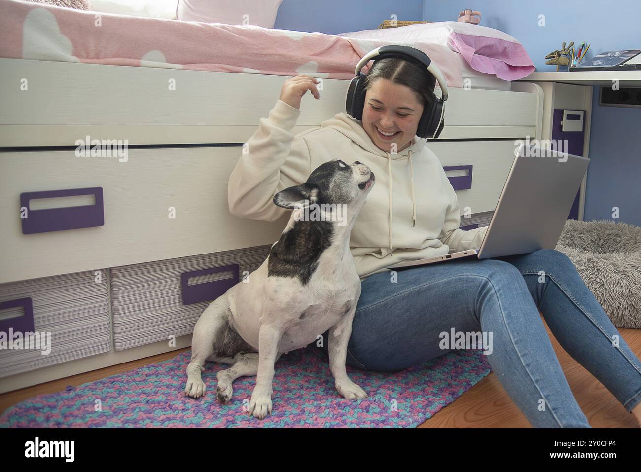 A teenager enjoys a moment of leisure in her room, working on her ...