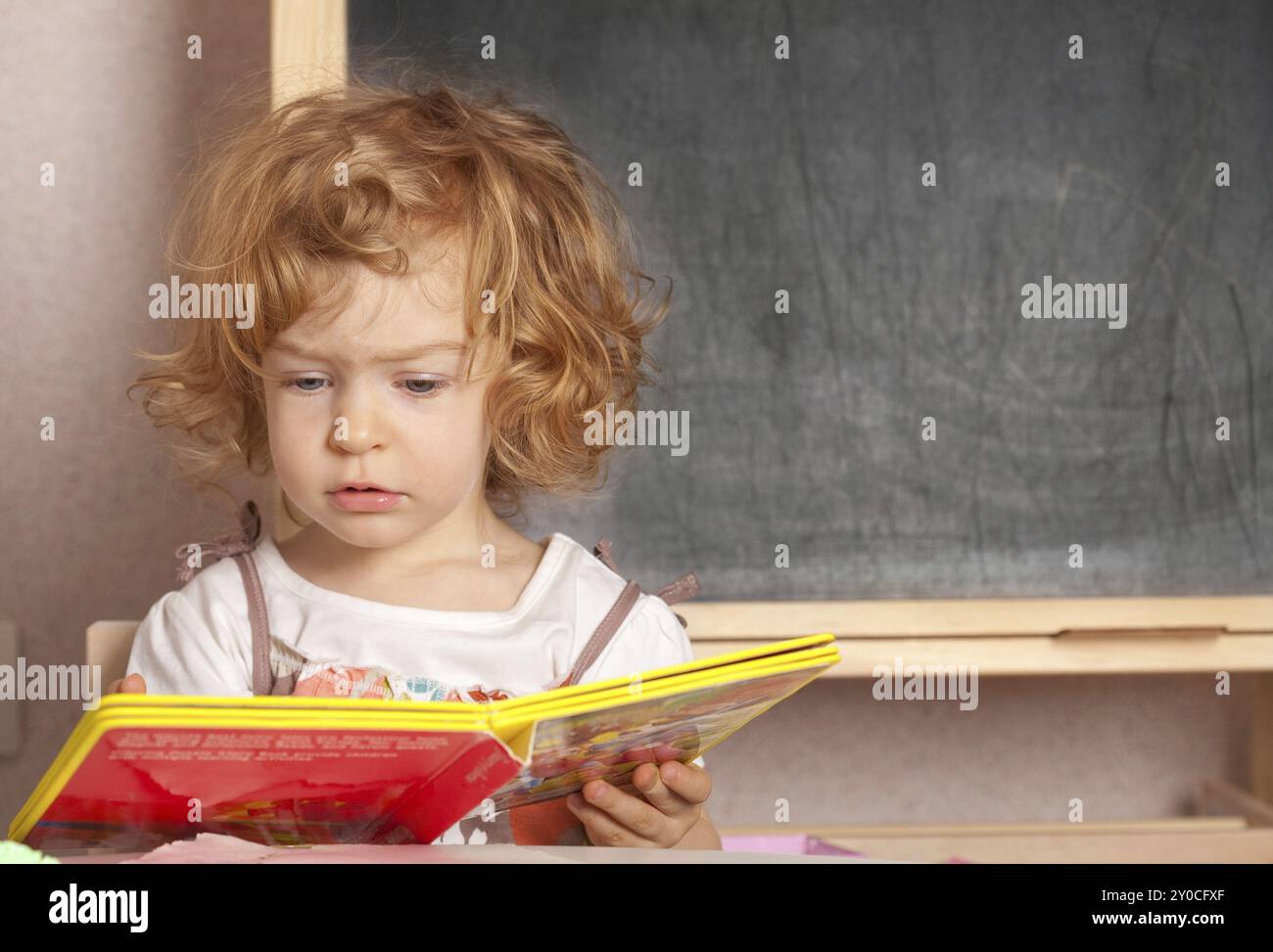 Schoolgirl reading textbook in a class against blackboard Stock Photo ...