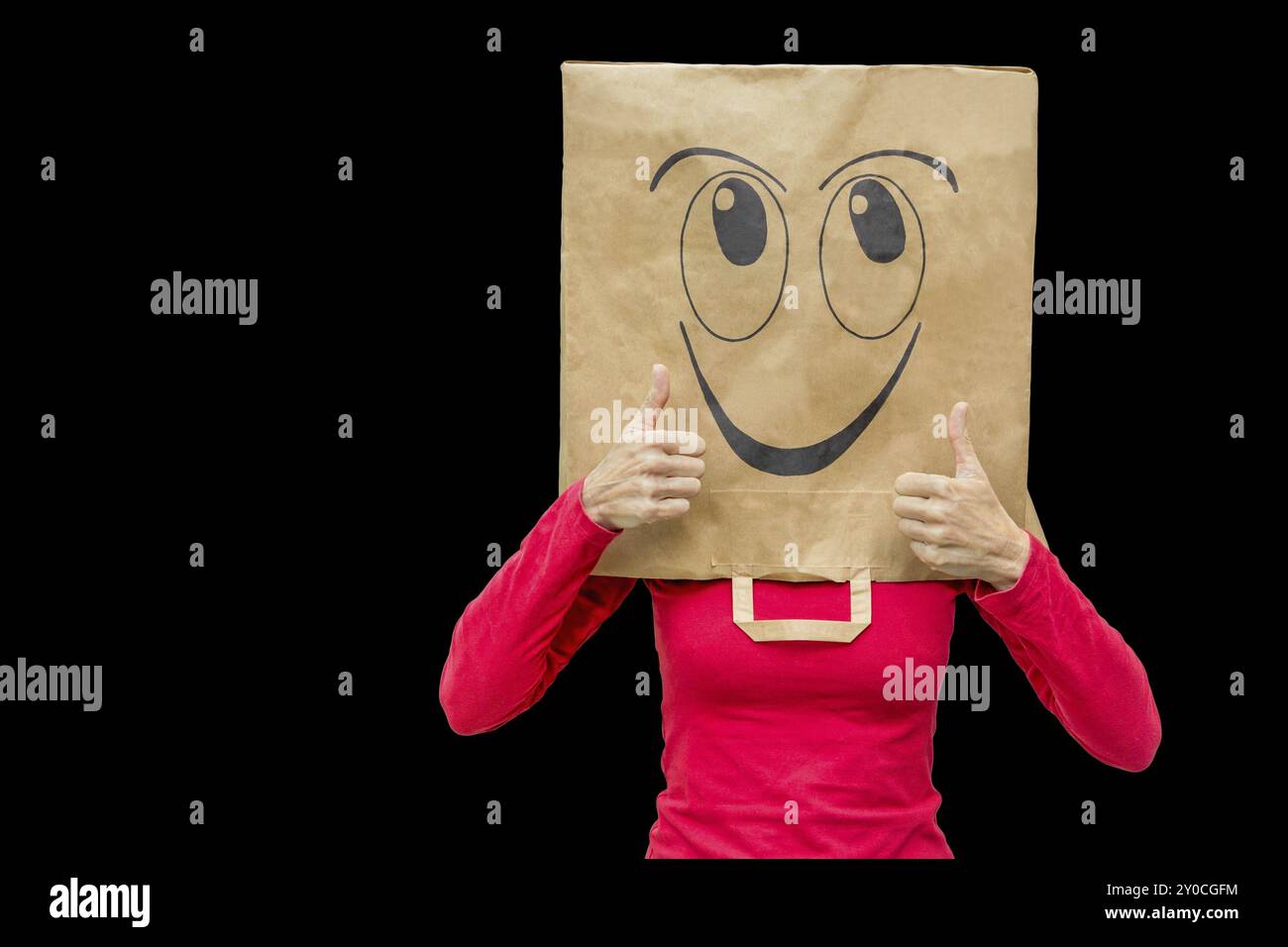 Woman wearing paper bag with happy face isolated on black. She is ...