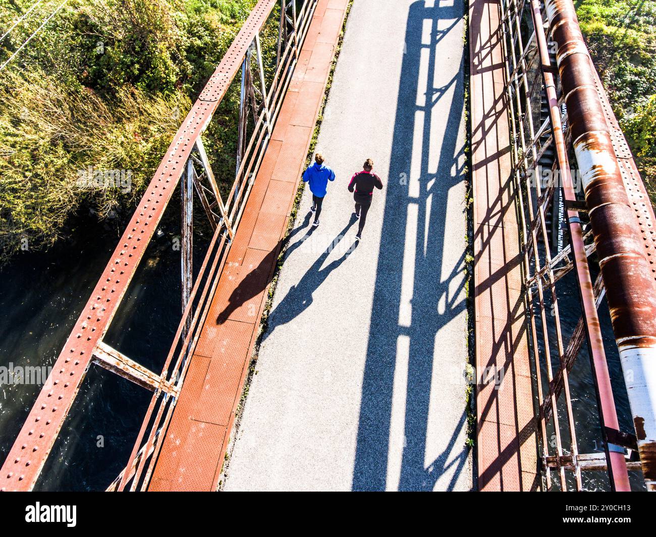 Aerial view of a runner running across bridge over the river. Morning ...