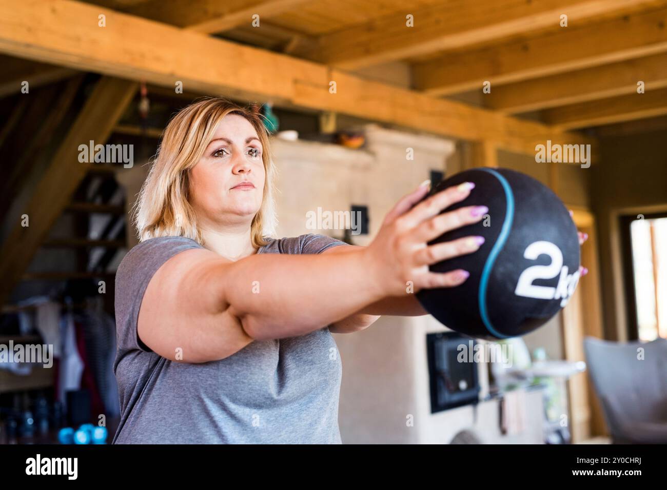 Overweight woman exercising at home, using weighted medicine ball ...