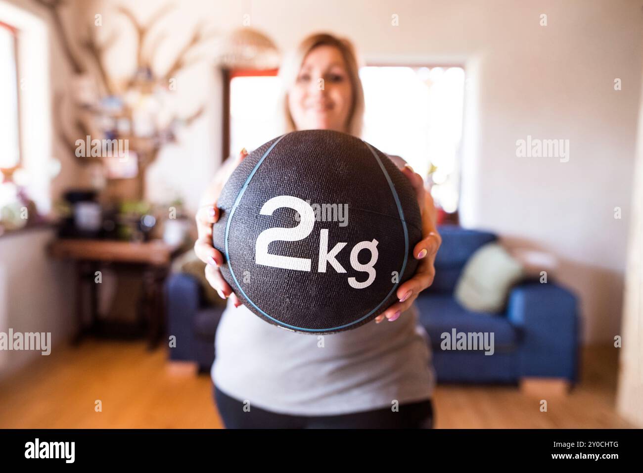 Overweight woman exercising at home, using weighted medicine ball ...