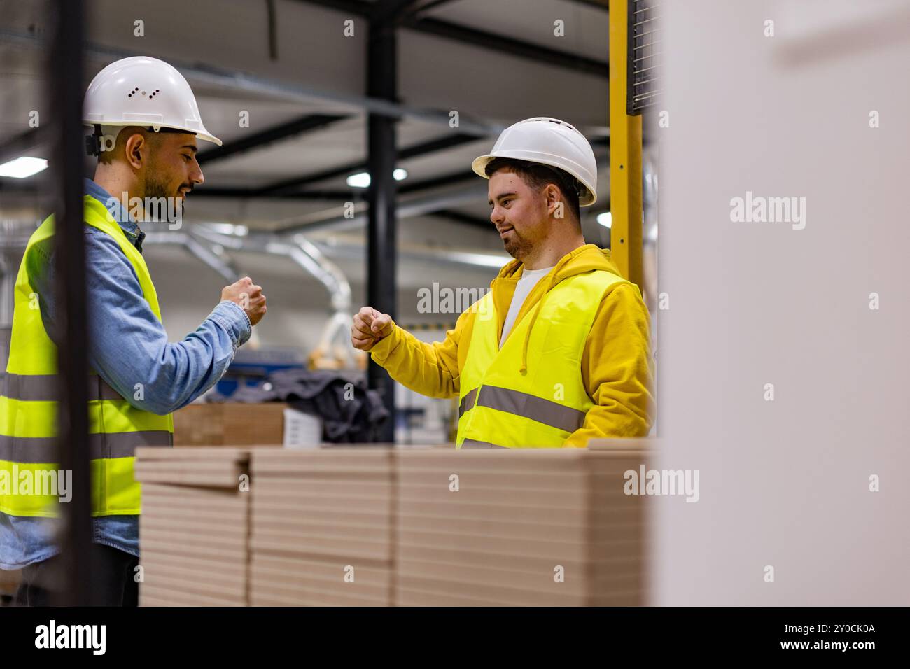 Young man with Down syndrome working in modern factory, fist bump with ...