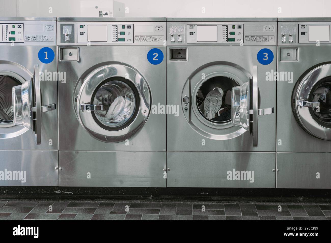 View of a modern stainless steel machines in a laundromat or laundrette ...
