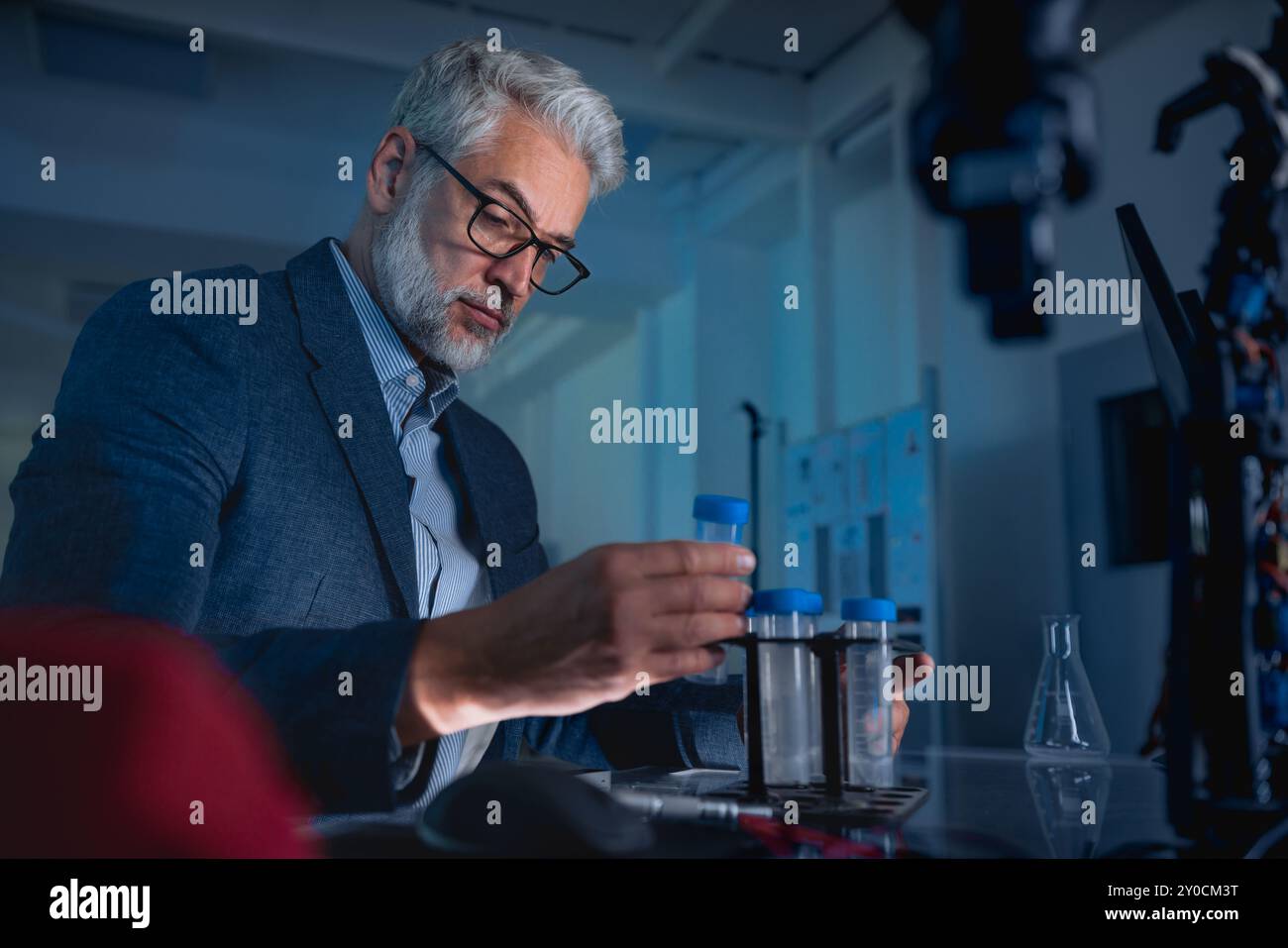 Scientist in the laboratory holding test tubes and intently looking at ...