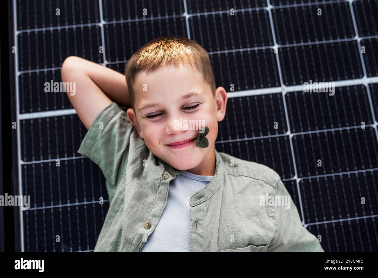 Top view of boy lying on roof with solar panels, looking at camera ...