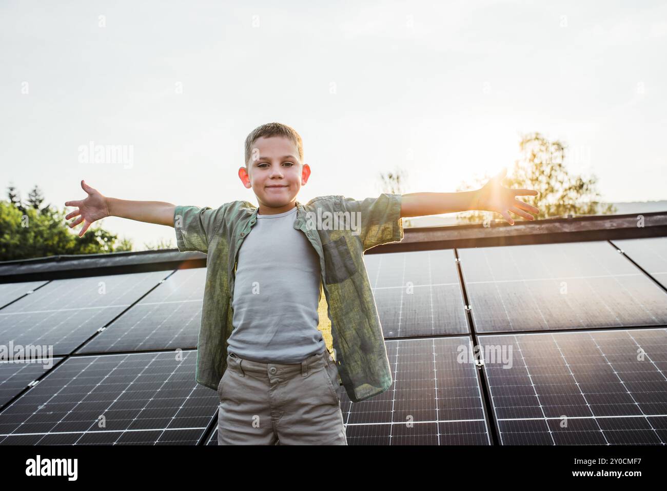 Cute boy standing on roof with solar panels with open arms. Rooftop ...
