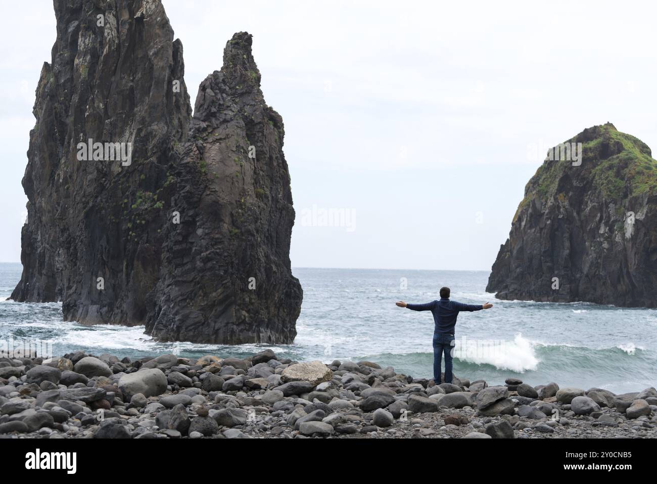 Man with arms wide open looking at Ribeira da Janela islet in Madeira ...