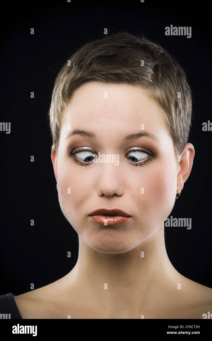 Pretty woman with short hair pulling faces in front of a black ...