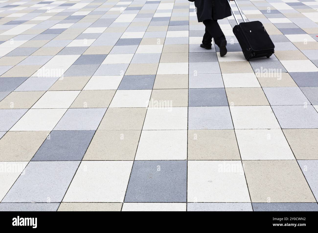 Man pulls trolley case over pavement Stock Photo - Alamy