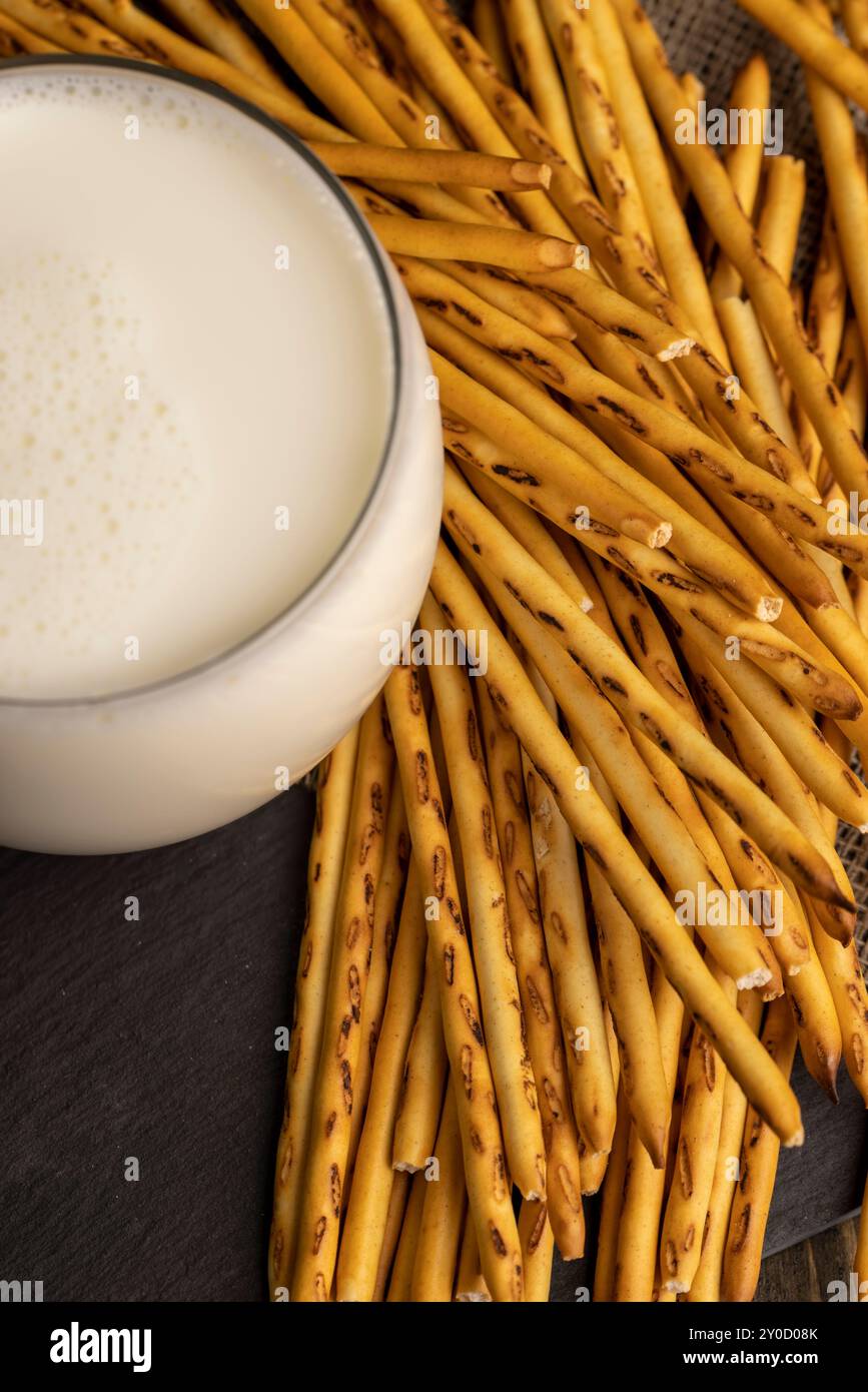 Thin and long bread sticks made of wheat flour and a glass of milk ...