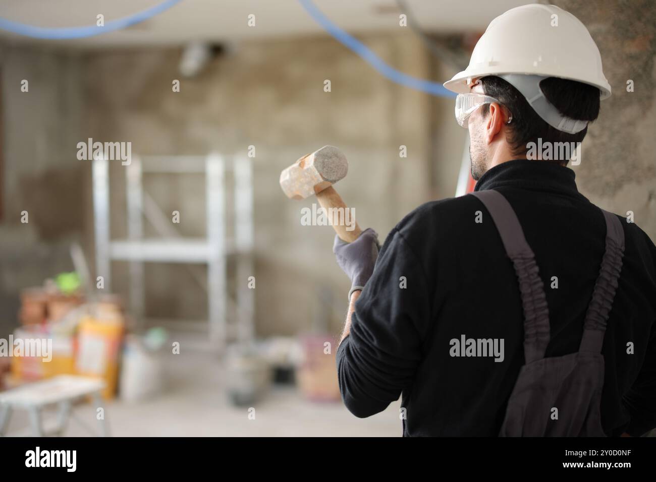 Back view of a construction worker holding sledgehammer reforming house ...