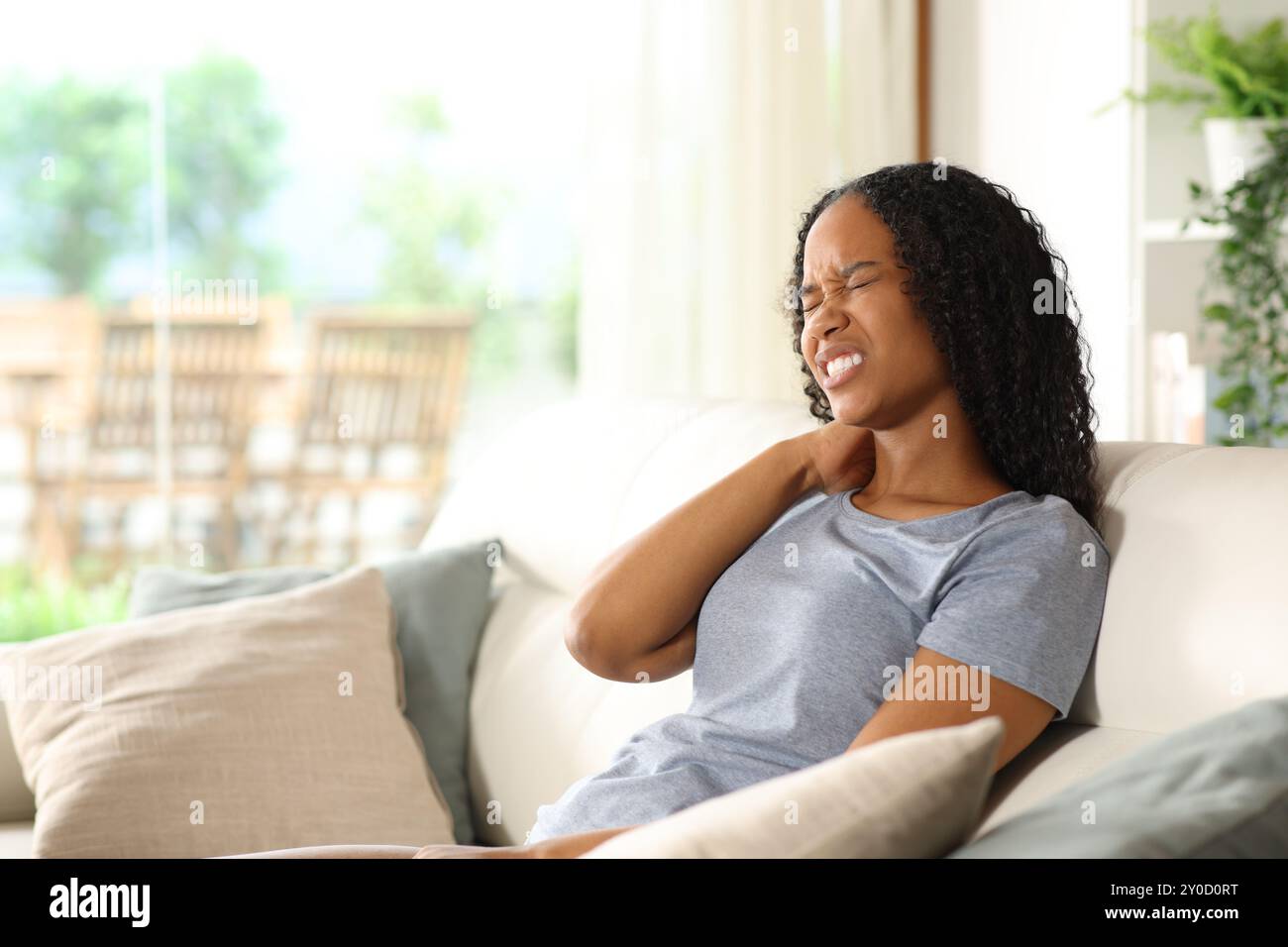 Black woman suffering neck ache sitting on uncomfortable sofa at home ...