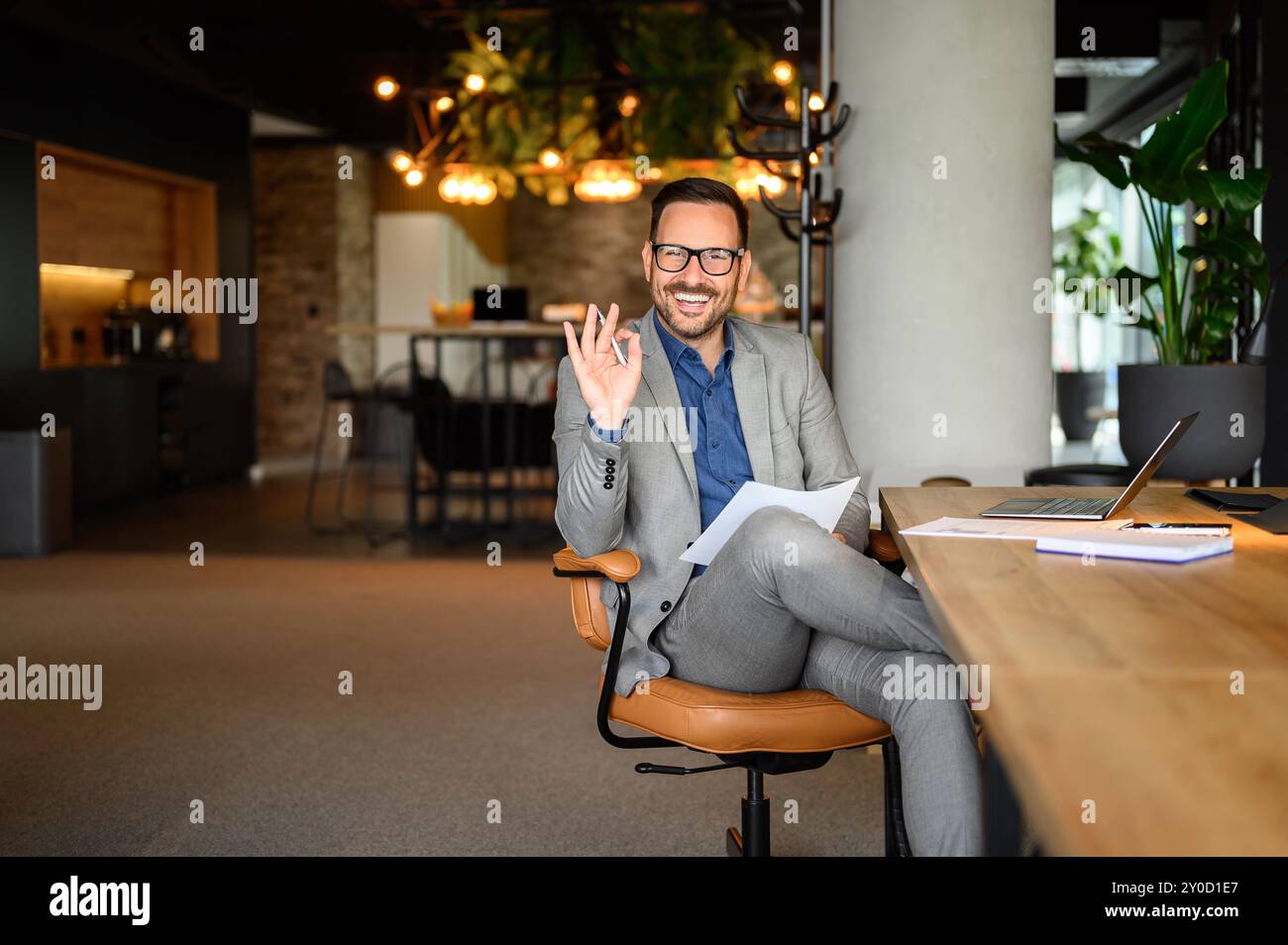 Portrait of smiling male entrepreneur with report showing OK sign while ...