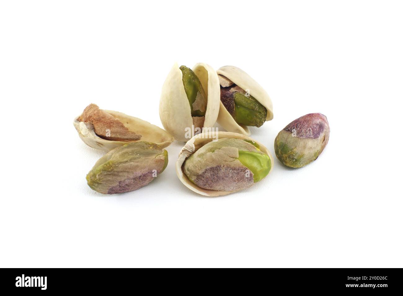 Pistachios are randomly spread across the white surface, some ...