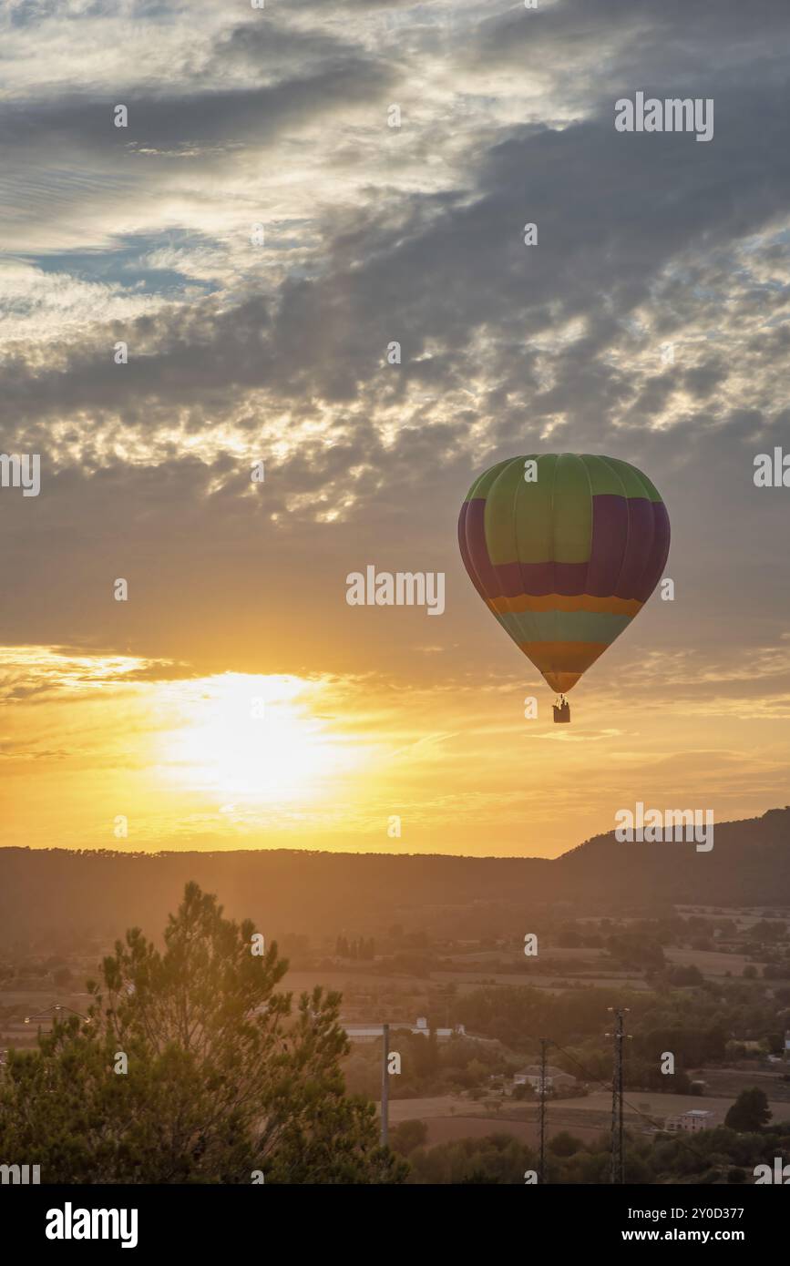 A colourful hot air balloon floats peacefully in a sunset sky with ...