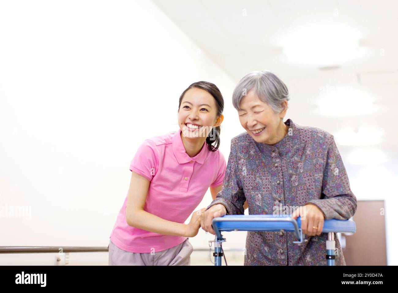 An elderly woman undergoing gait training with a woman caregiver by her ...