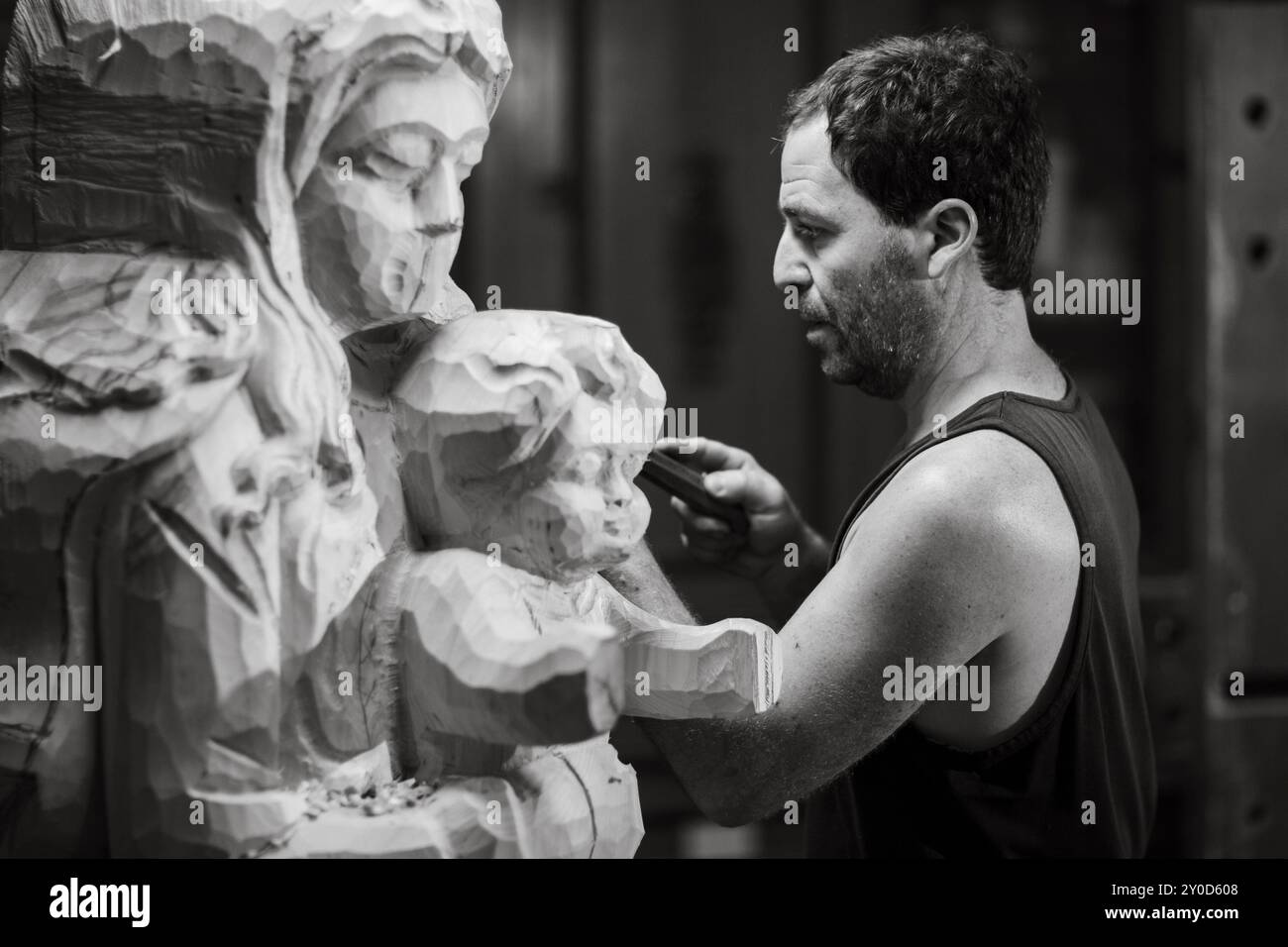 Close up of an artist's hands as they work on a wooden statue, using a ...