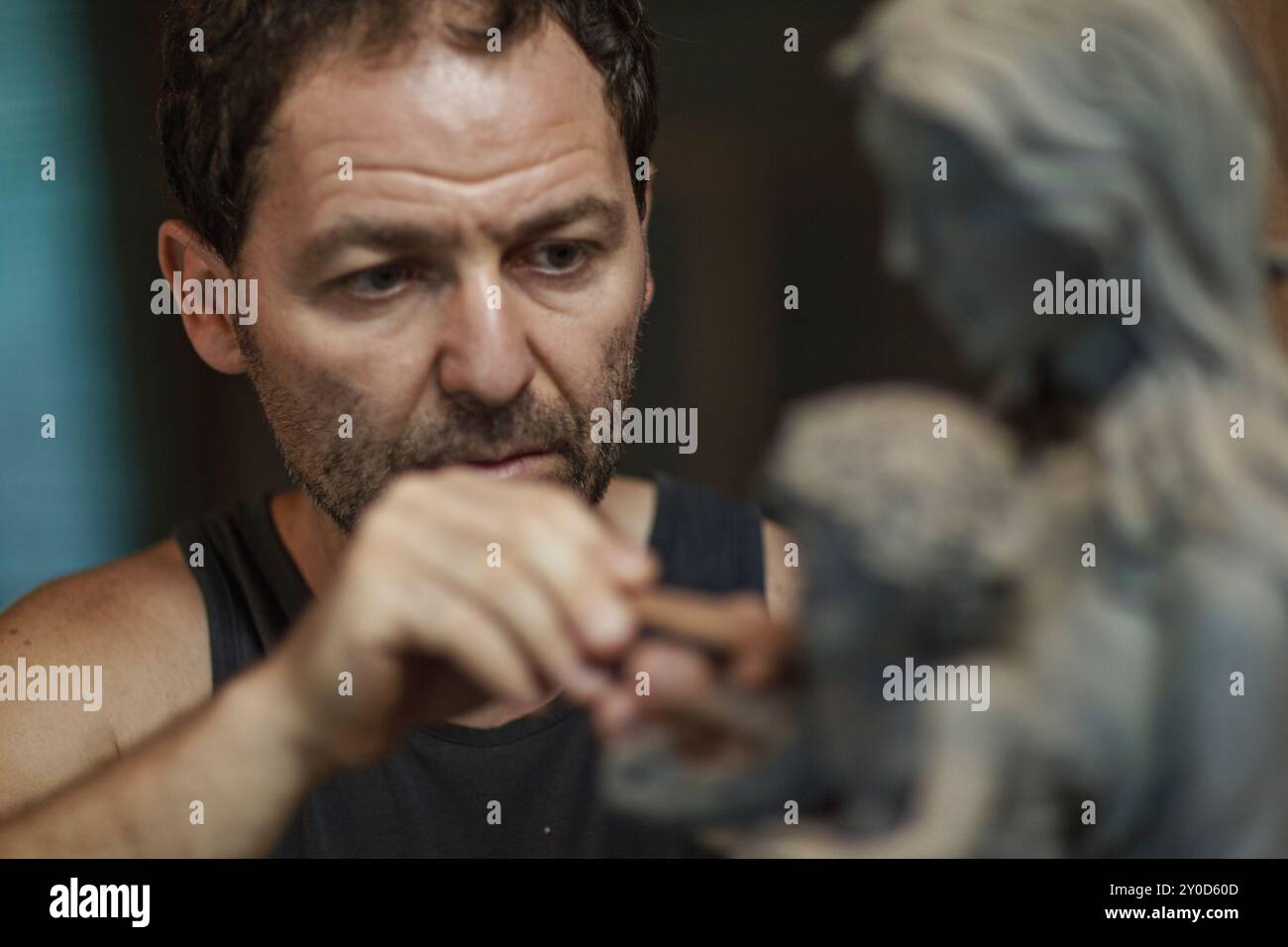 Sculptor is using a chisel to carve a piece of wood, creating a ...