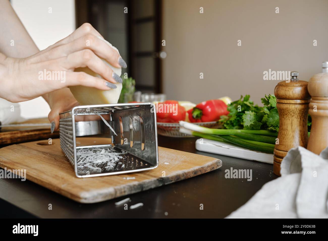 Female hands grating goat cheese using metal grater in the kitchen ...