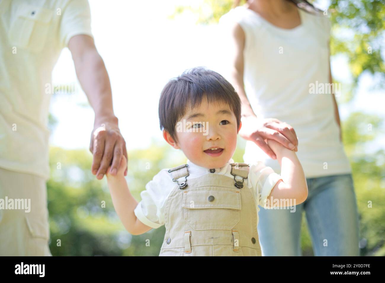 Boy walking hand in hand with parents Stock Photo - Alamy