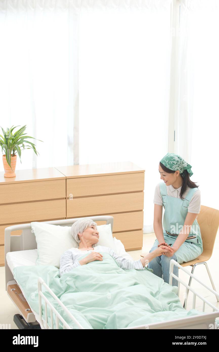 An elderly in bed and a care helper Stock Photo - Alamy