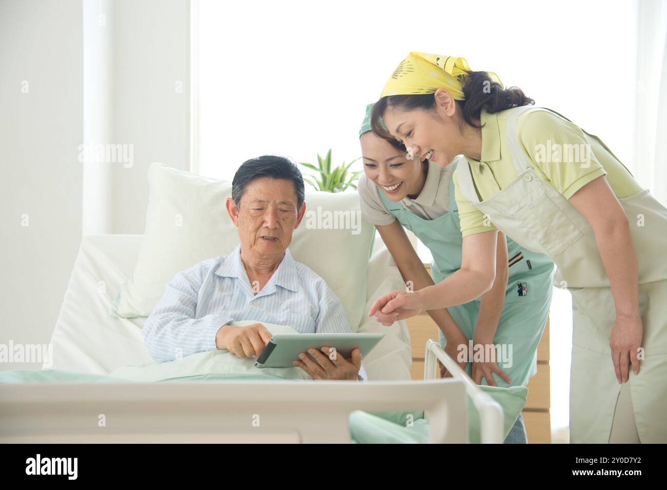 An elderly in bed and a care helper Stock Photo - Alamy