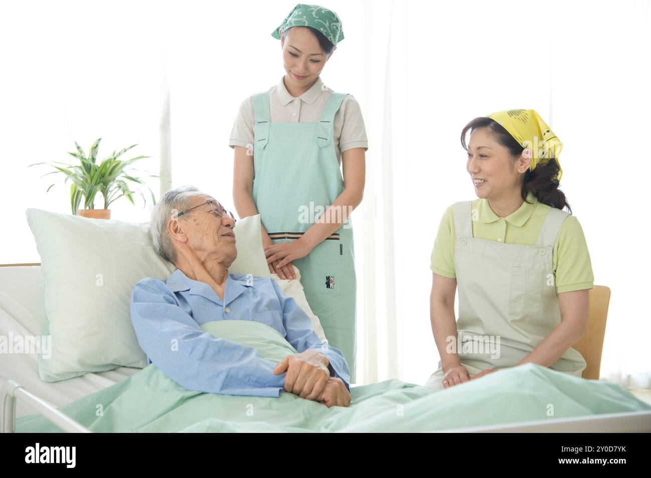An elderly in bed and a care helper Stock Photo - Alamy