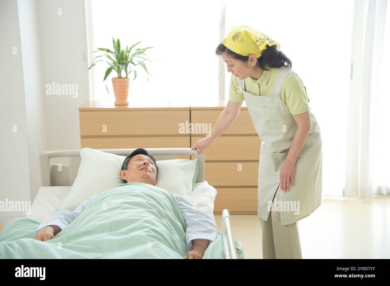 An elderly in bed and a care helper Stock Photo - Alamy