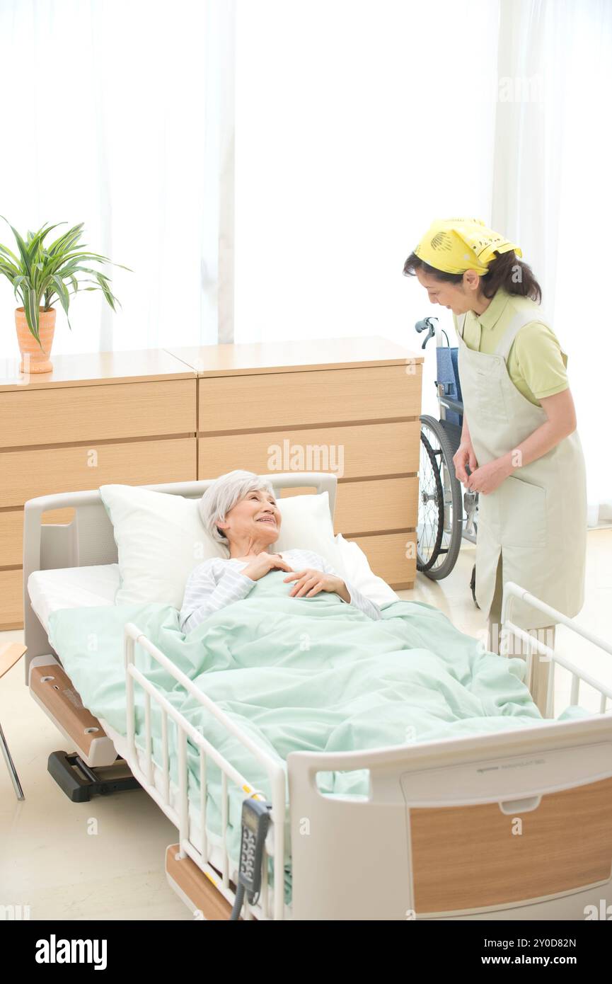 An elderly in bed and a care helper Stock Photo - Alamy