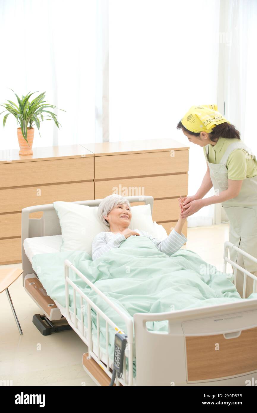 An elderly in bed and a care helper Stock Photo - Alamy