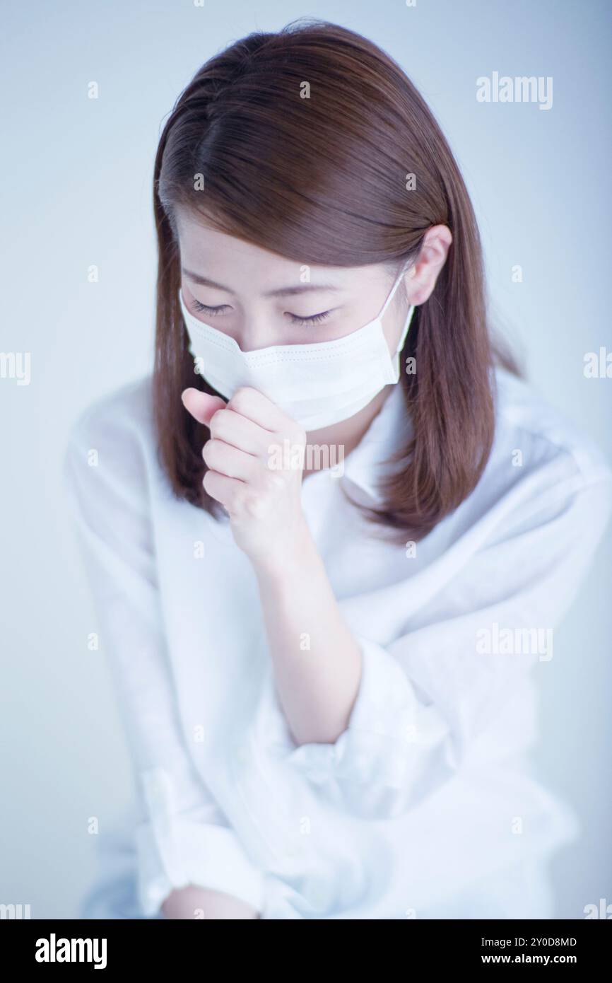 A woman in a coughing fit while wearing a mask Stock Photo - Alamy