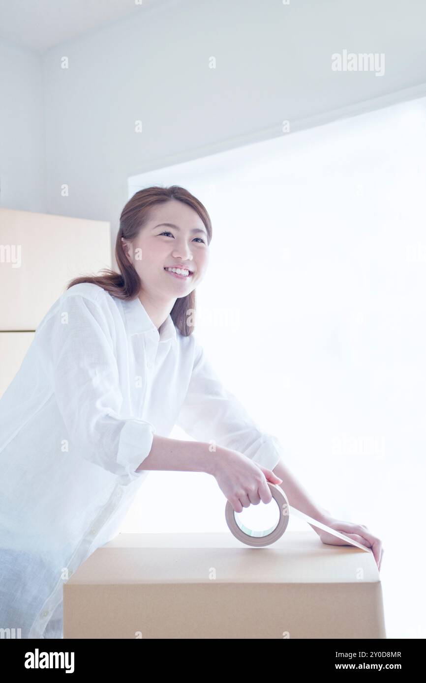 A woman busy packing for a move with a smile on her face Stock Photo ...