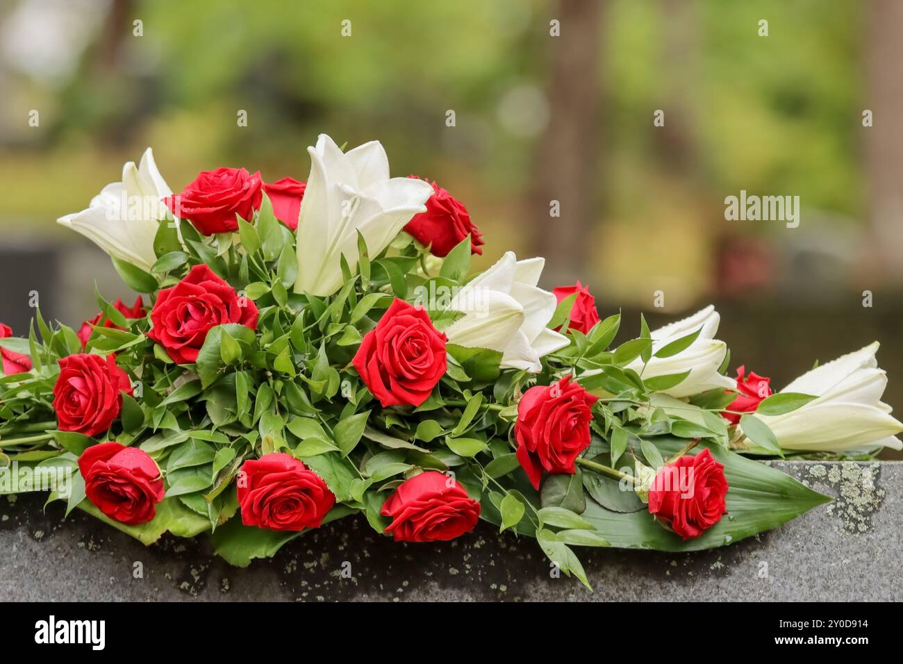 Red and white funeral flowers on a gravestone in a cemetery. Relatives ...