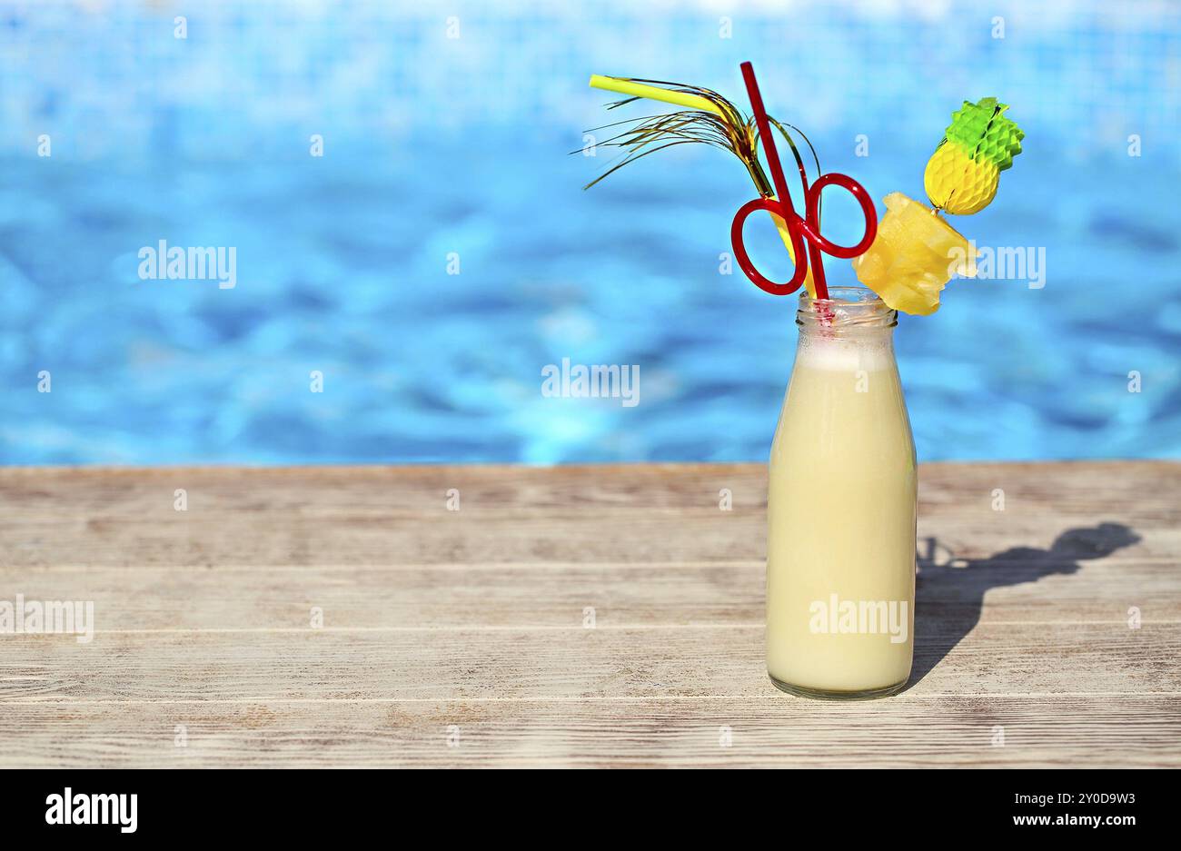 Glass of pinacolada cocktail standing on the swimming pool ledge in an ...