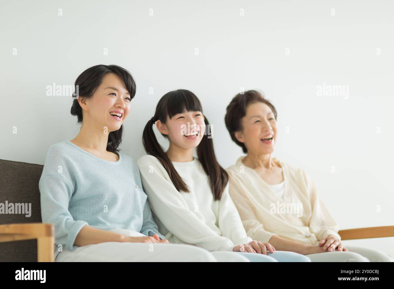 Family of three generations sitting on a sofa Stock Photo - Alamy