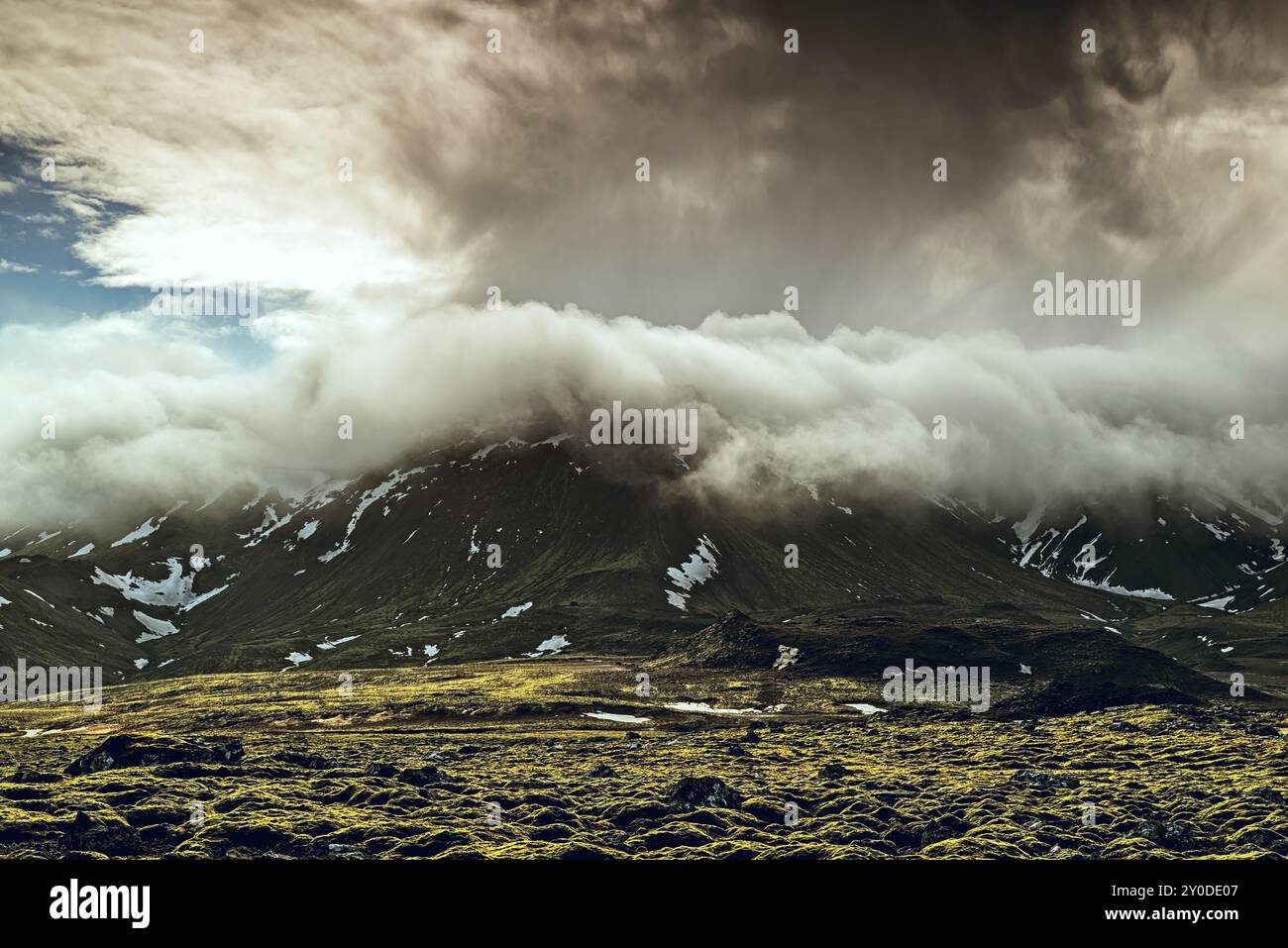 Majestic clouds roll over a mountain range, casting dramatic shadows on ...