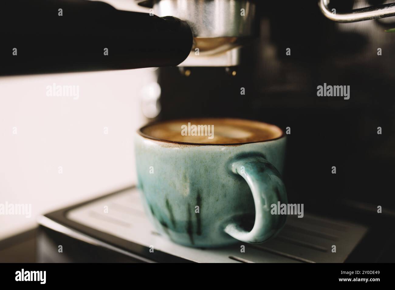 Green cup of coffee at the coffee maker machine, coffee time. Blurred ...