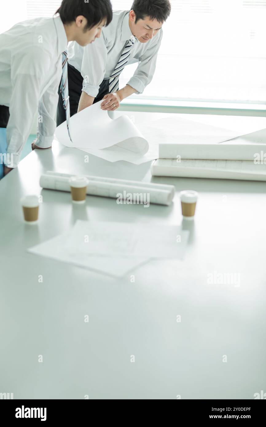 A businessman spreading a drawing over a table and having an ...
