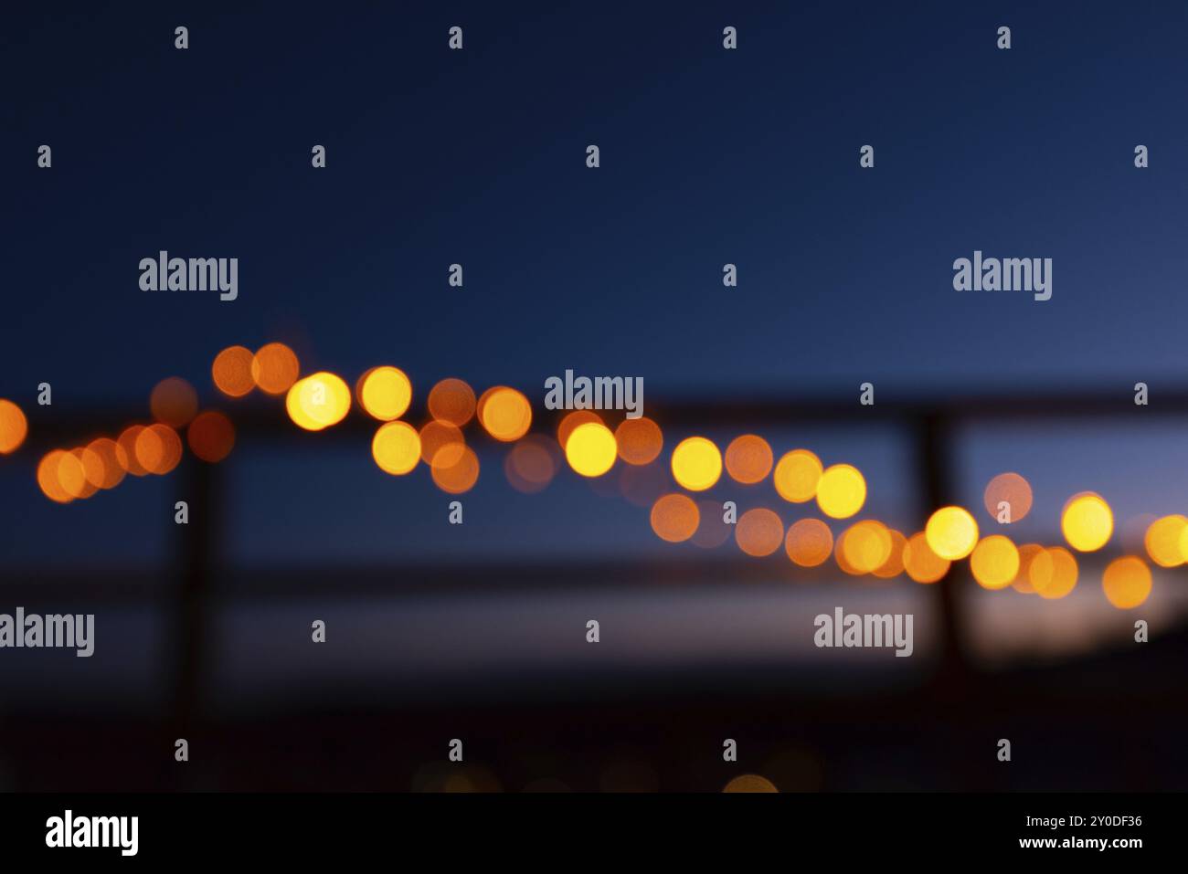 Out of focus christmas lights on the railings of a balcony at night ...