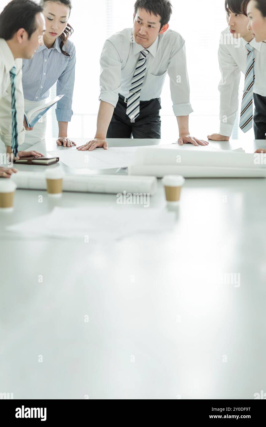 A businessman and businesswoman spreading a drawing over a table and ...