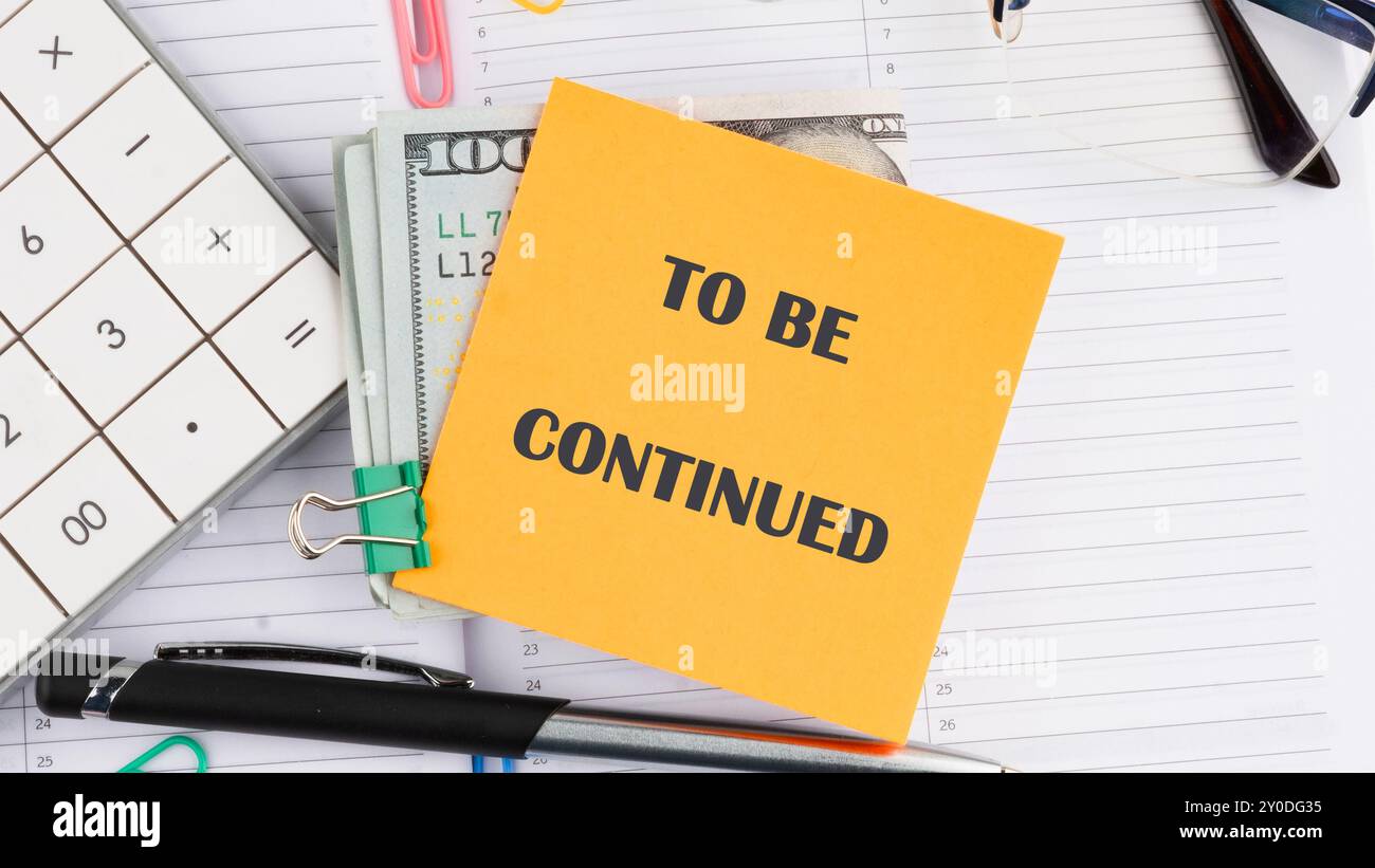 TO BE CONTINUED text written on a yellow sticker on top of dollar bills ...