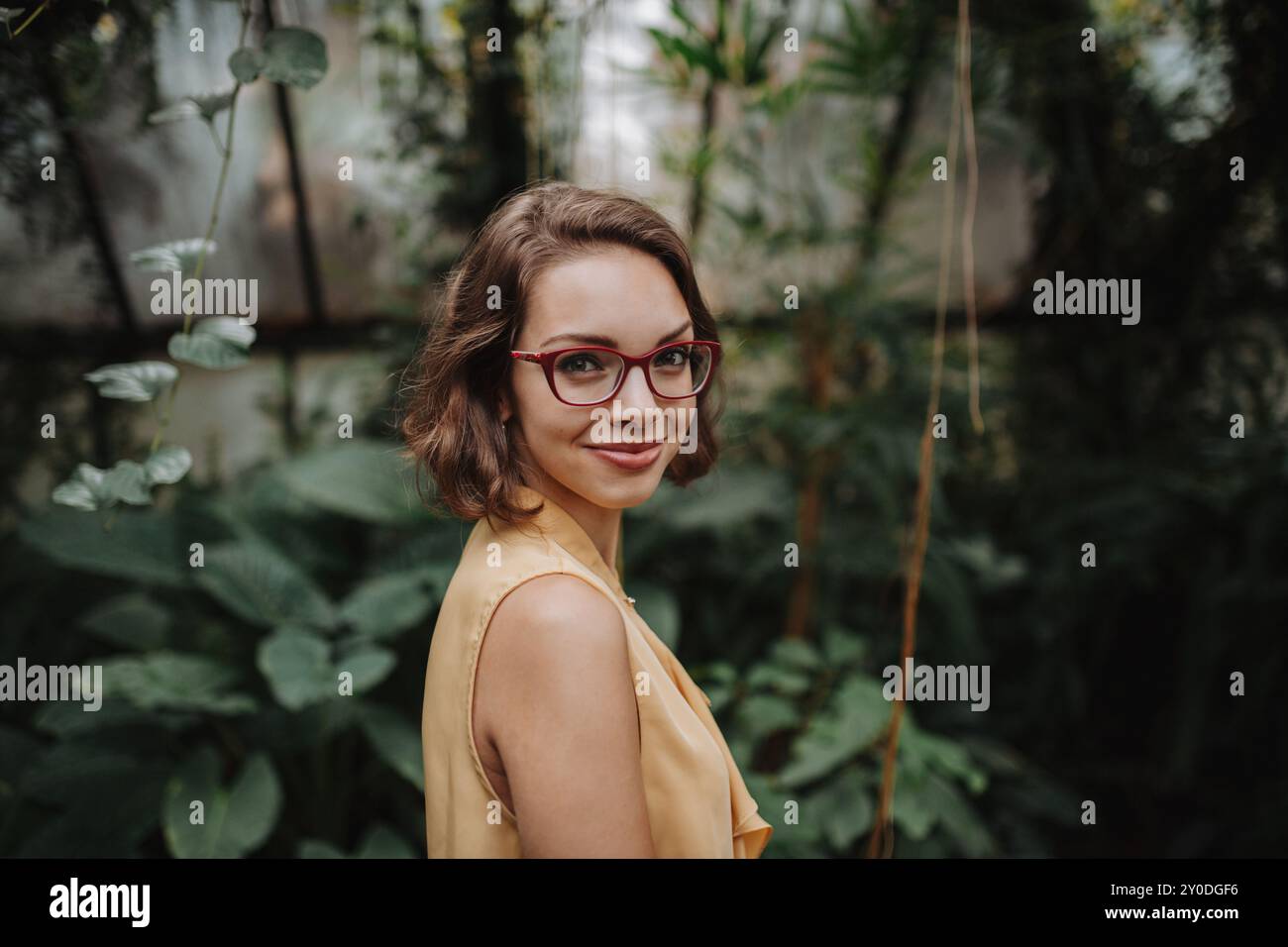 Beautiful woman standing in botanical garden, in the middle of lush ...