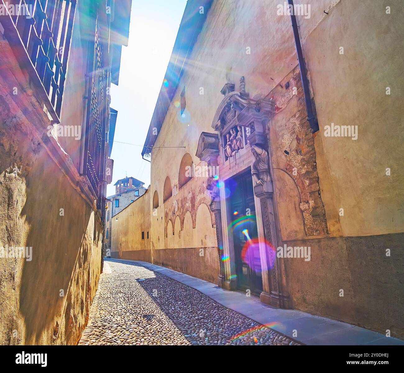 The medieval facade of San Grata Church with lens flare on sunny Via ...