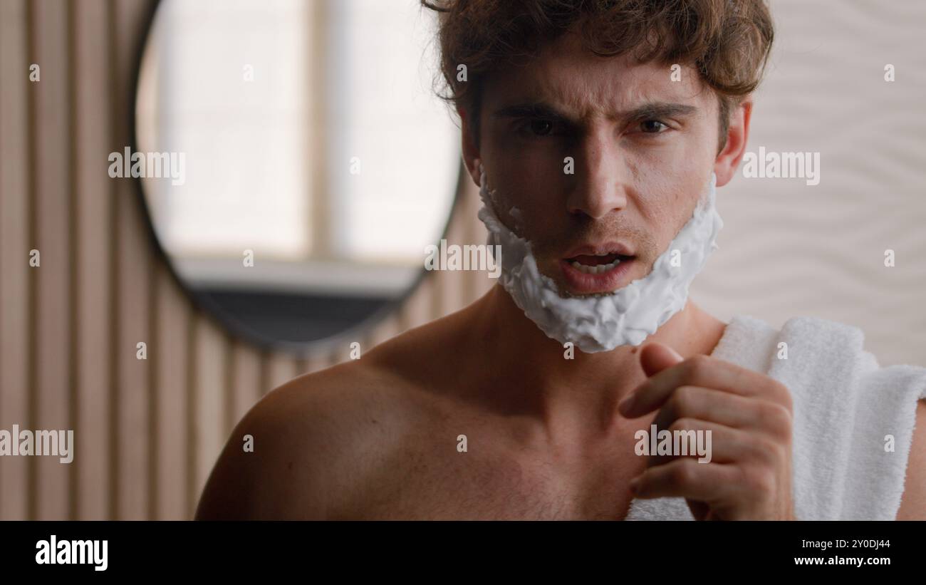 Funny happy Caucasian millennial silly man singing in shaving razor ...