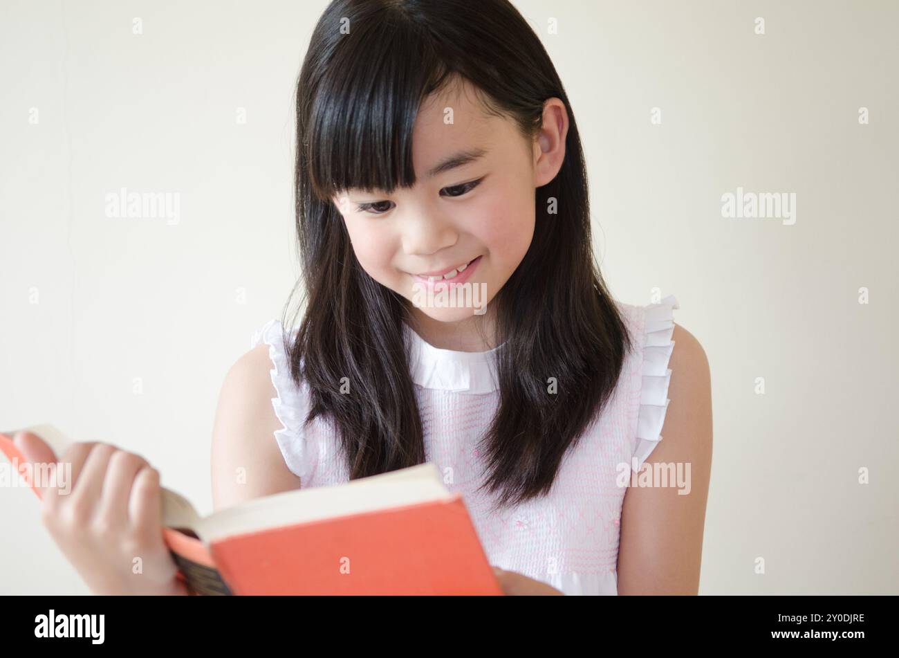 A girl smiling while reading a book Stock Photo - Alamy