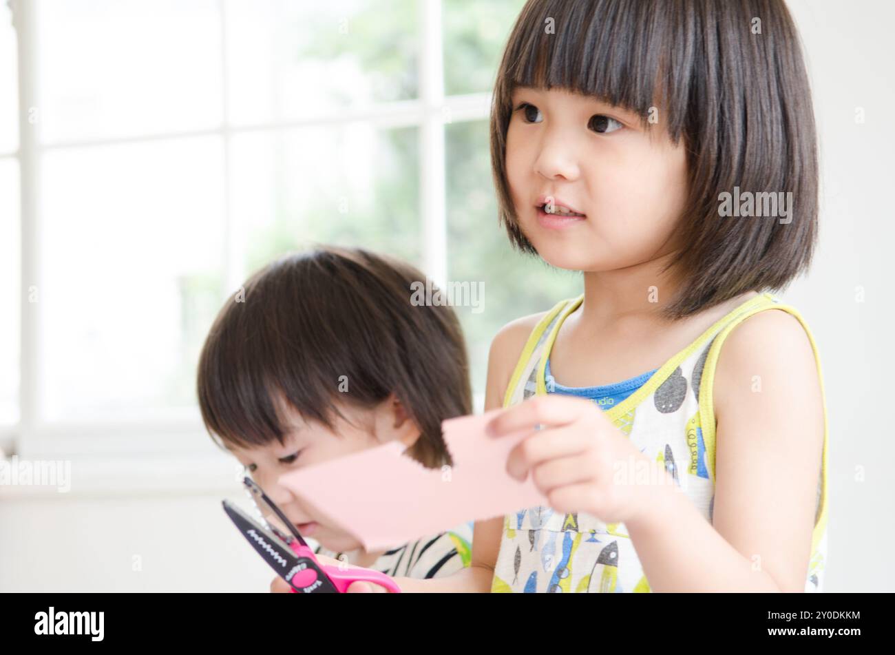 A girl and boy cutting a piece of paper Stock Photo - Alamy