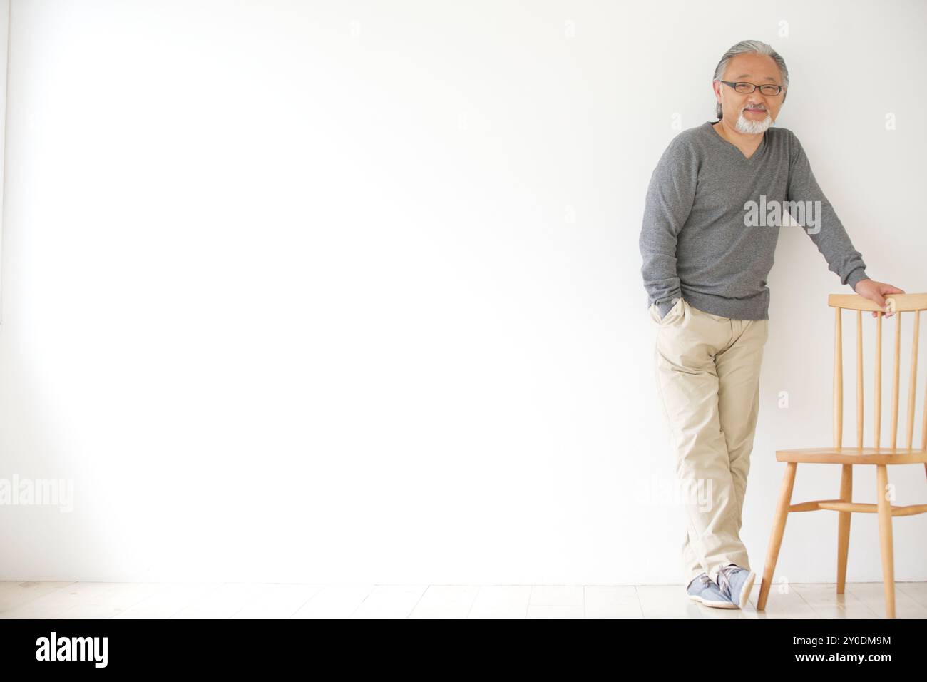 An elderly man standing with his hand on a chair Stock Photo - Alamy