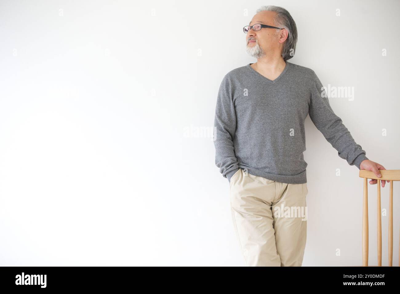 An elderly man standing with his hand on a chair Stock Photo - Alamy